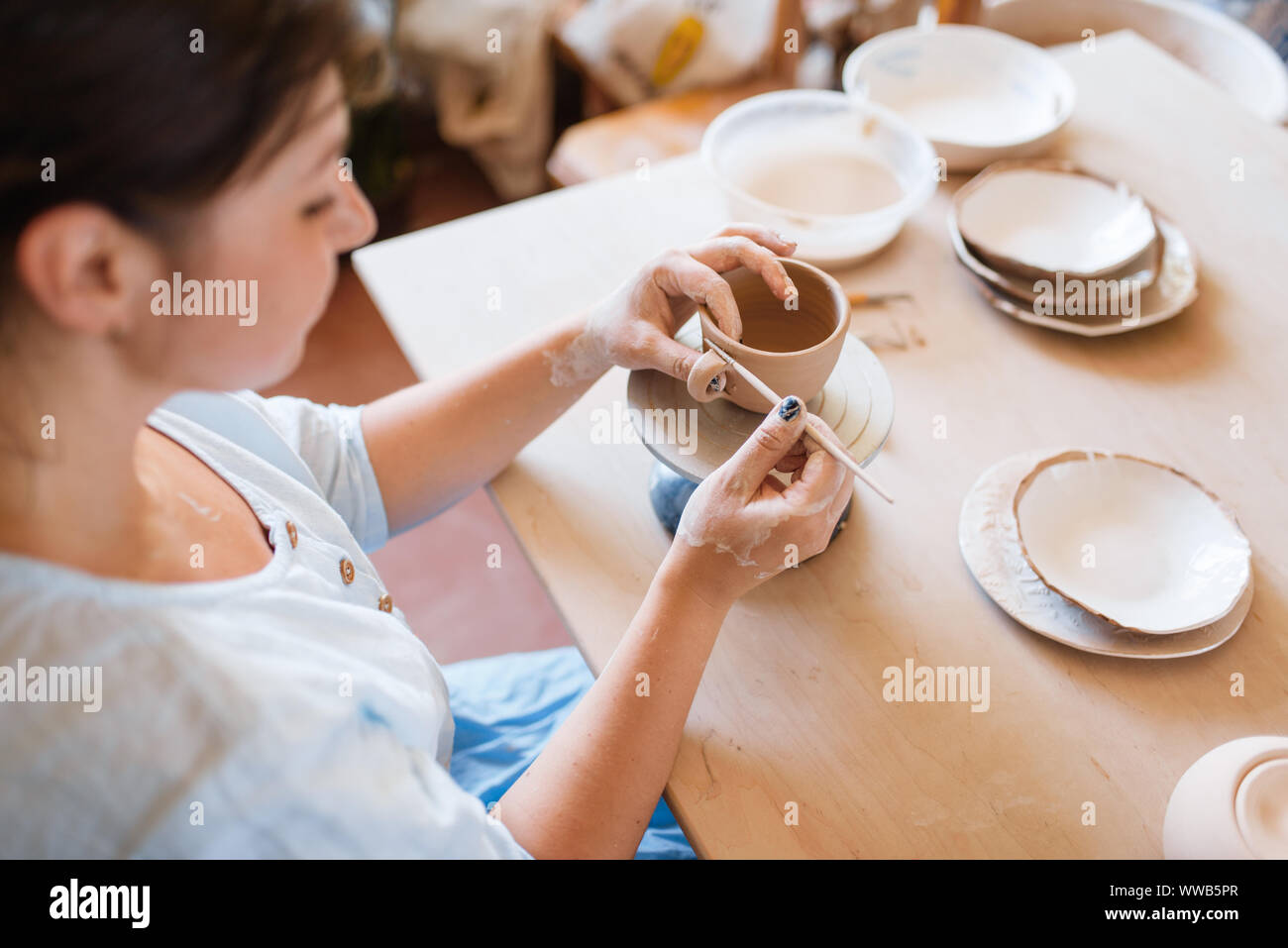 Female potter skins pot with a spatula, pottery Stock Photo - Alamy