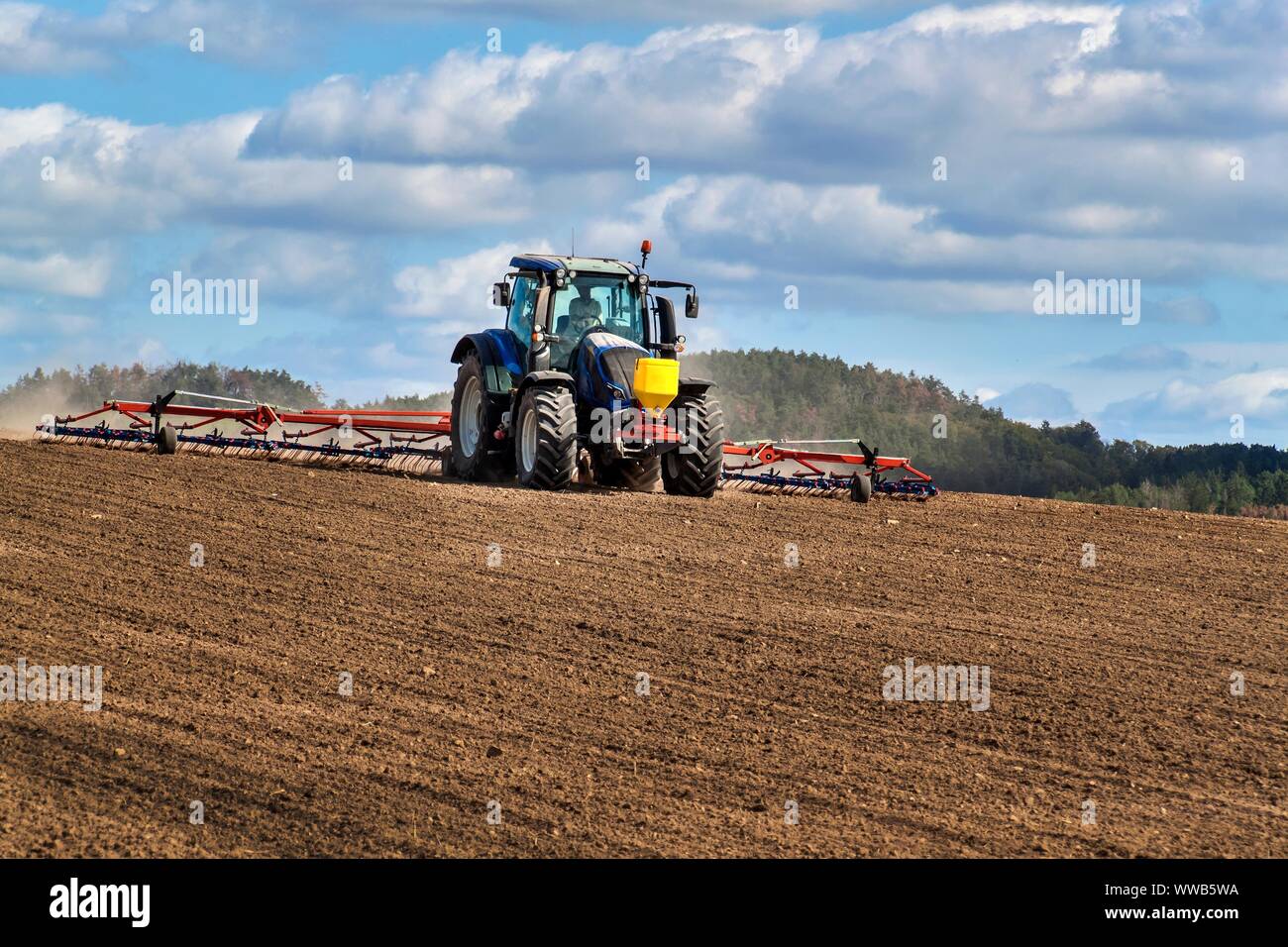 A blue tractor sows grain. Farm work on a farm in the Czech Republic ...