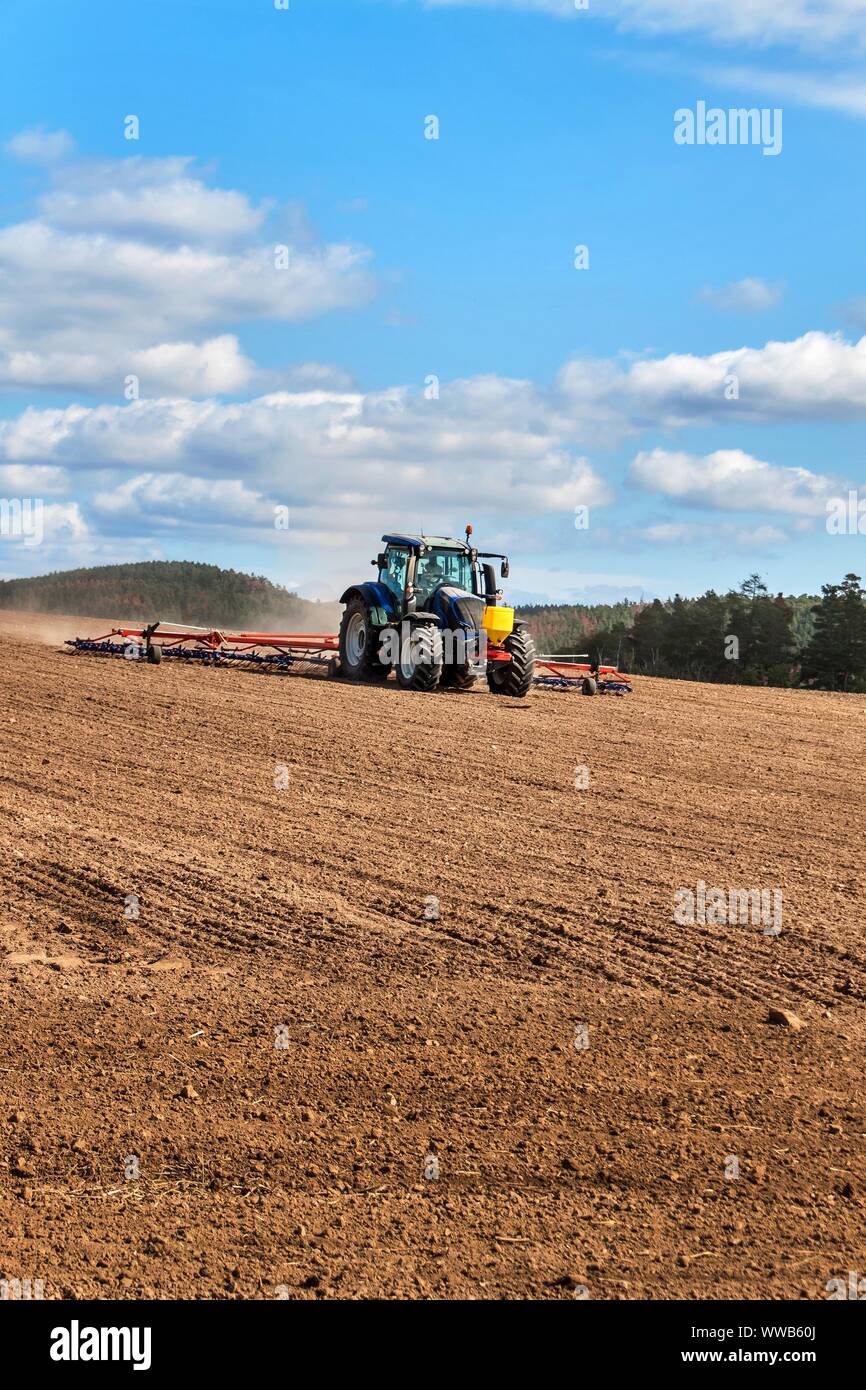 A blue tractor sows grain. Farm work on a farm in the Czech Republic ...