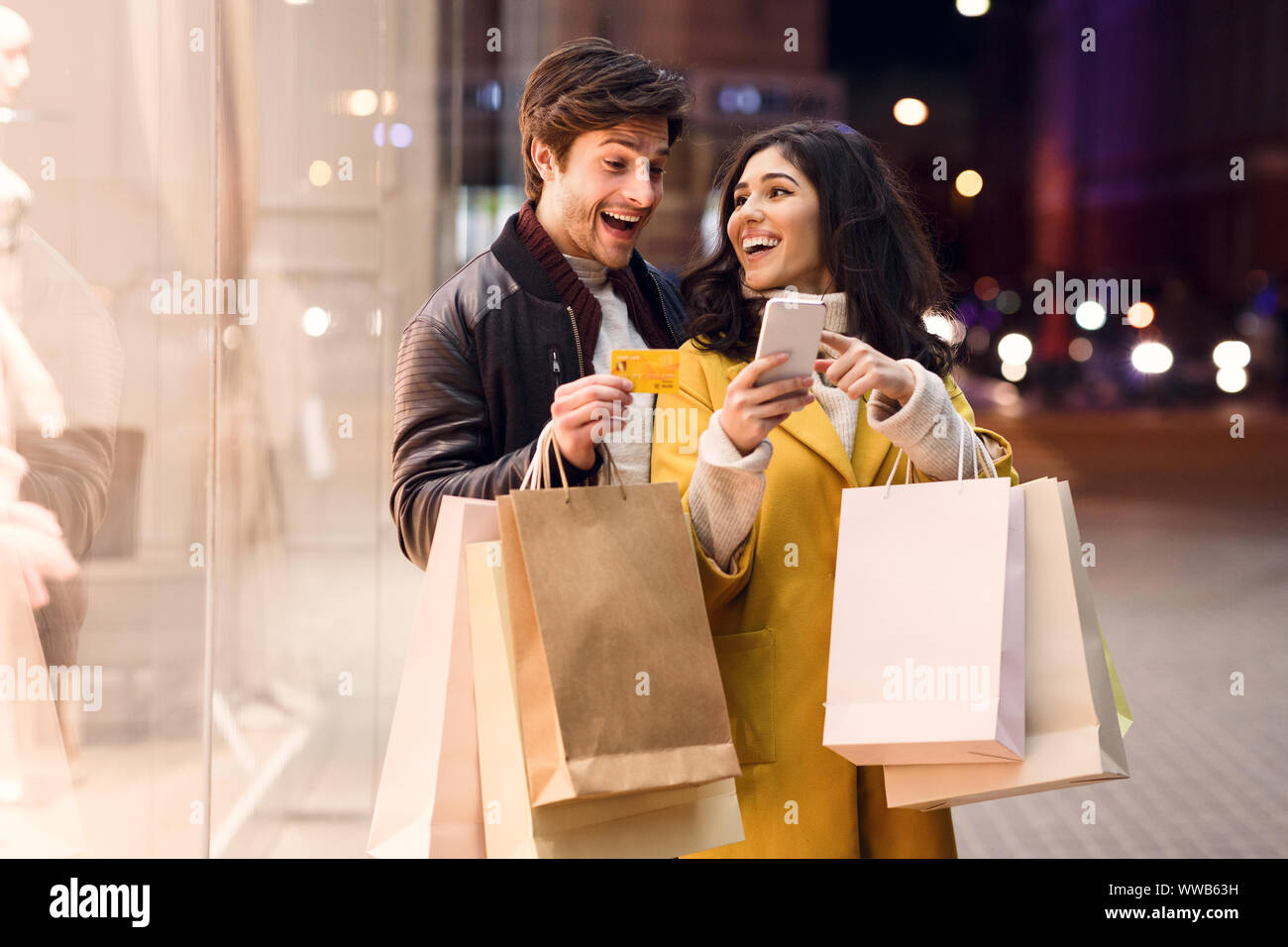 Consumerism concept. Happy couple checking cellphone outdoors Stock ...