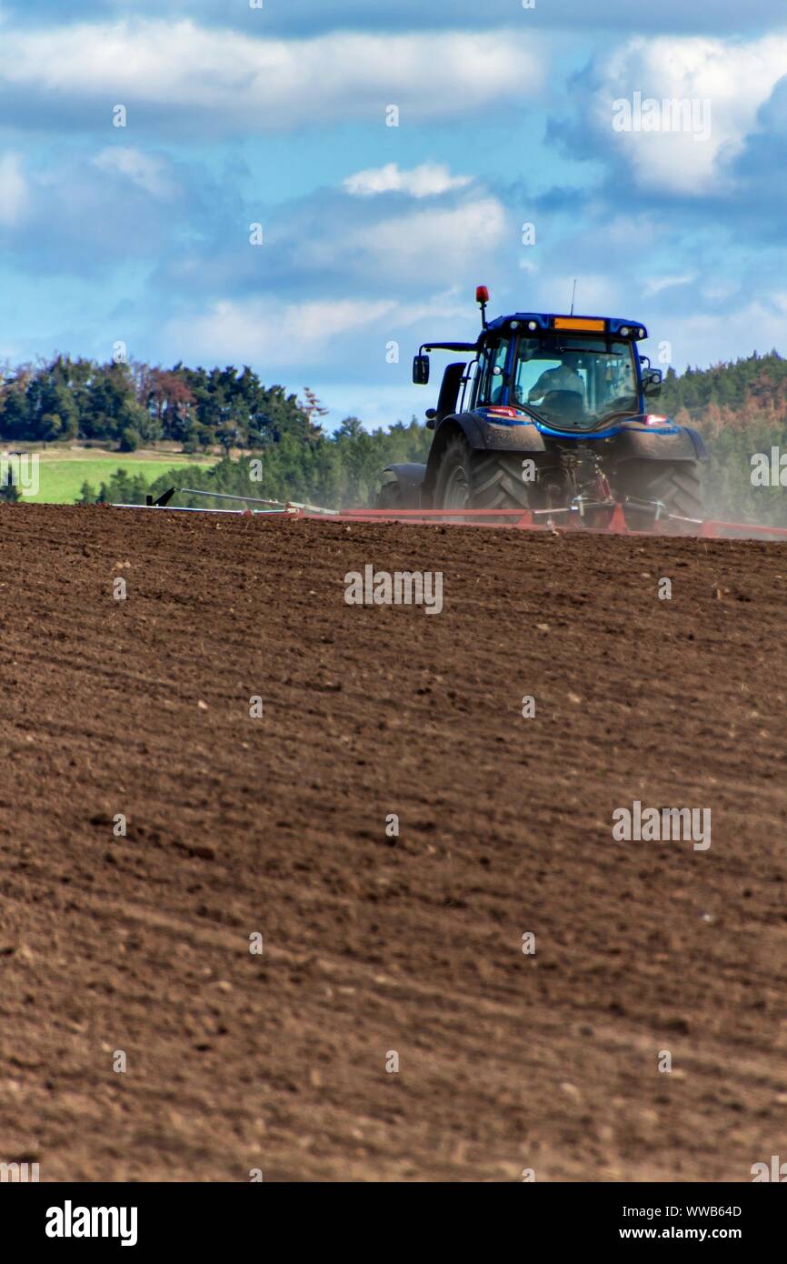 A blue tractor sows grain. Farm work on a farm in the Czech Republic ...