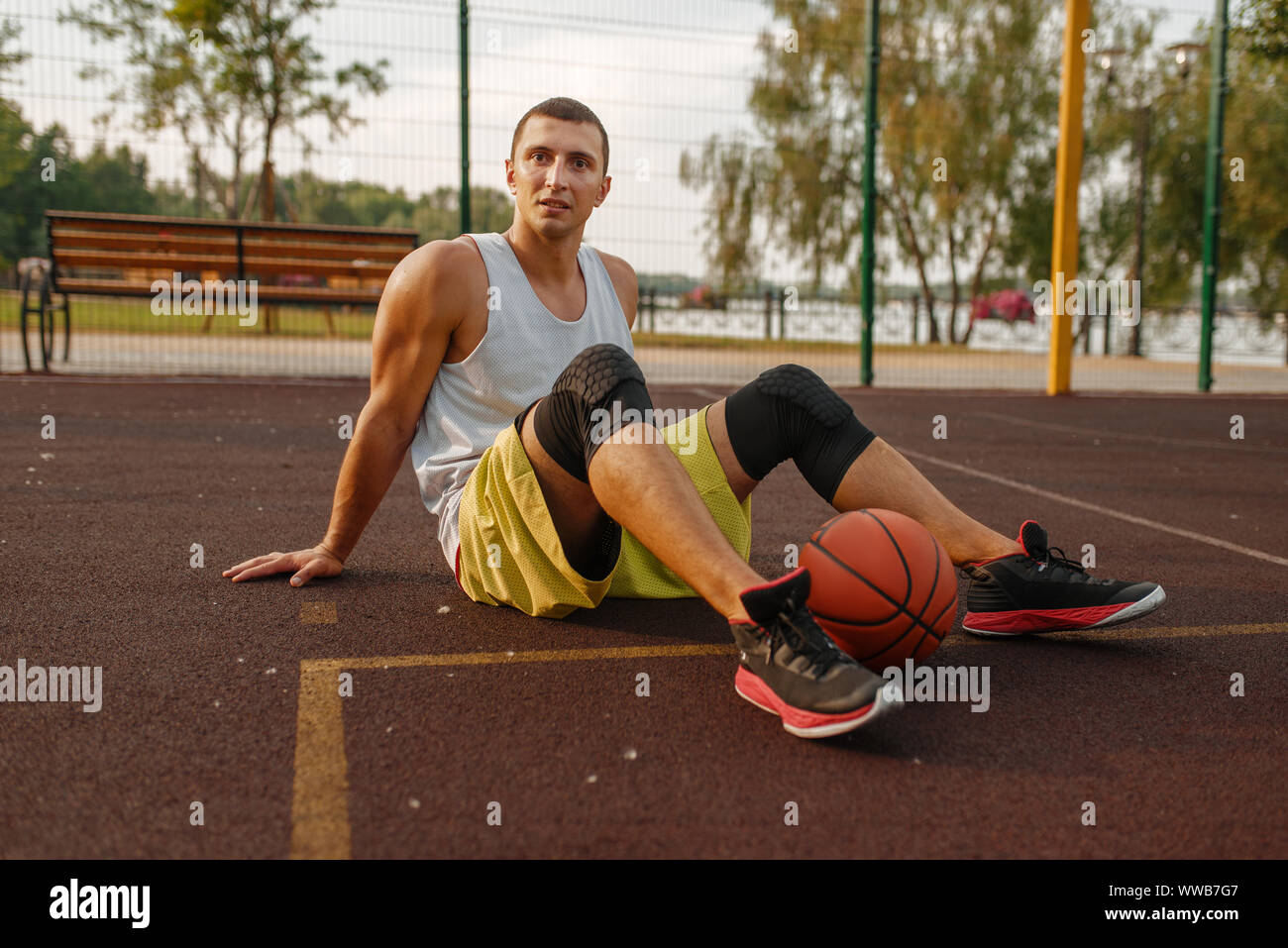 Basketball player with ball sitting on the ground Stock Photo - Alamy