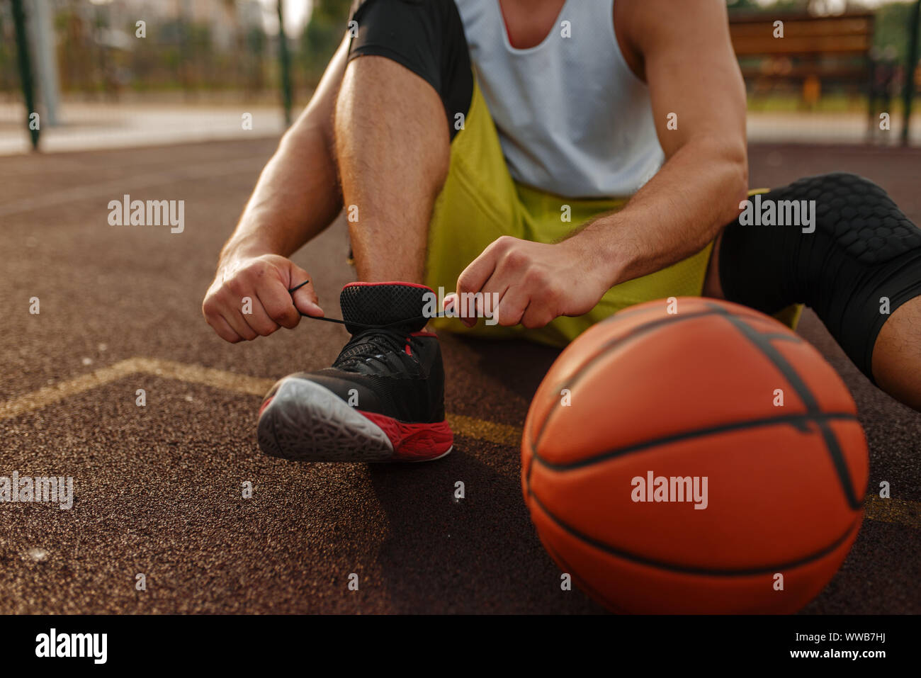 Basketball player tying laces on outdoor court Stock Photo - Alamy
