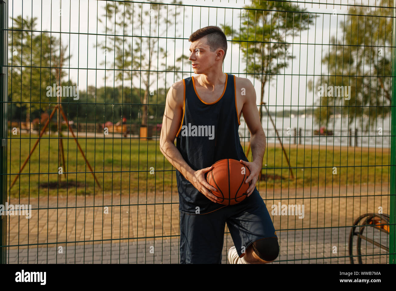 Basketball player standing at the mesh fence Stock Photo - Alamy