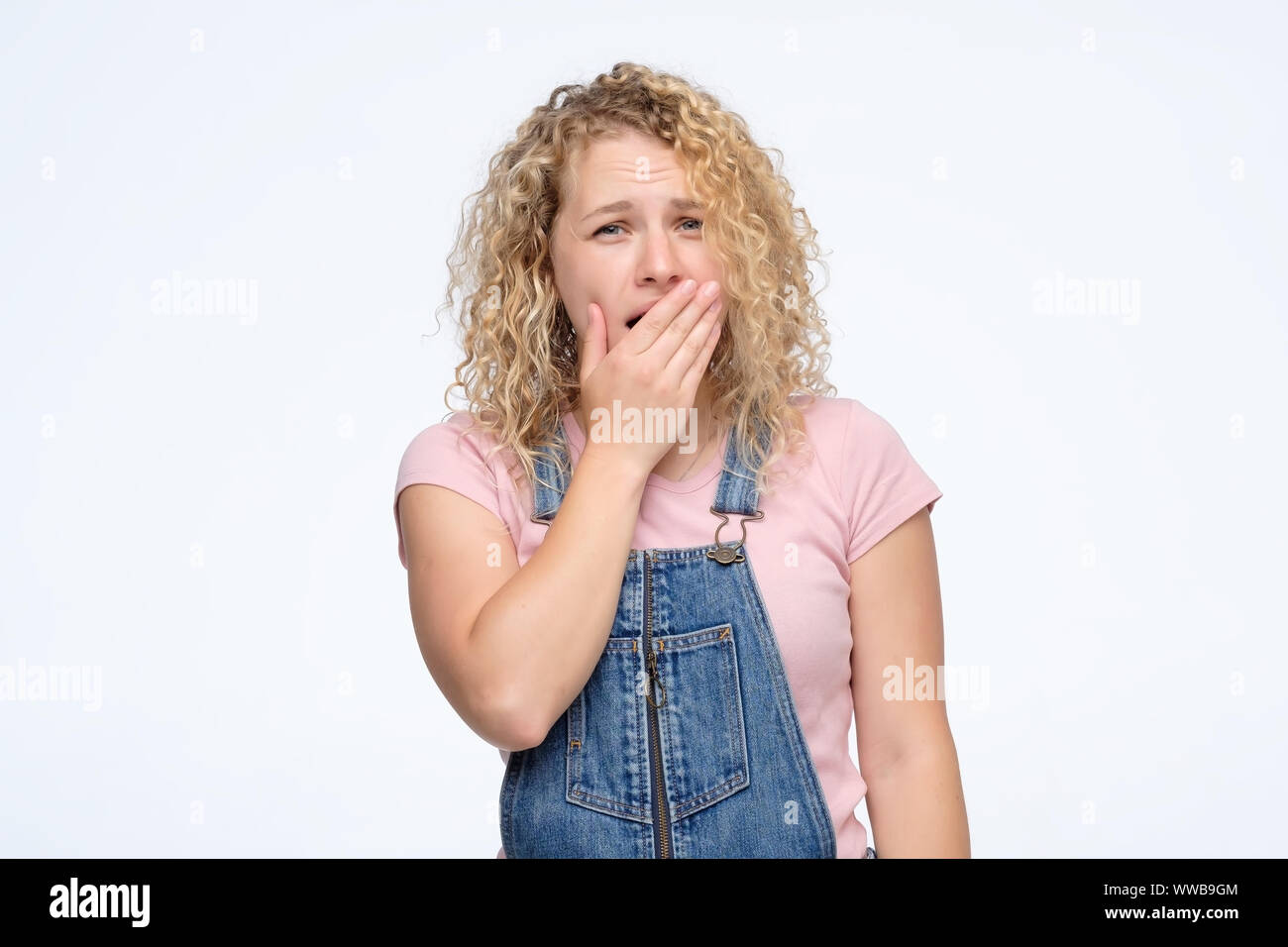 Yawning curly girl stretches herself after hard working day. Being ...