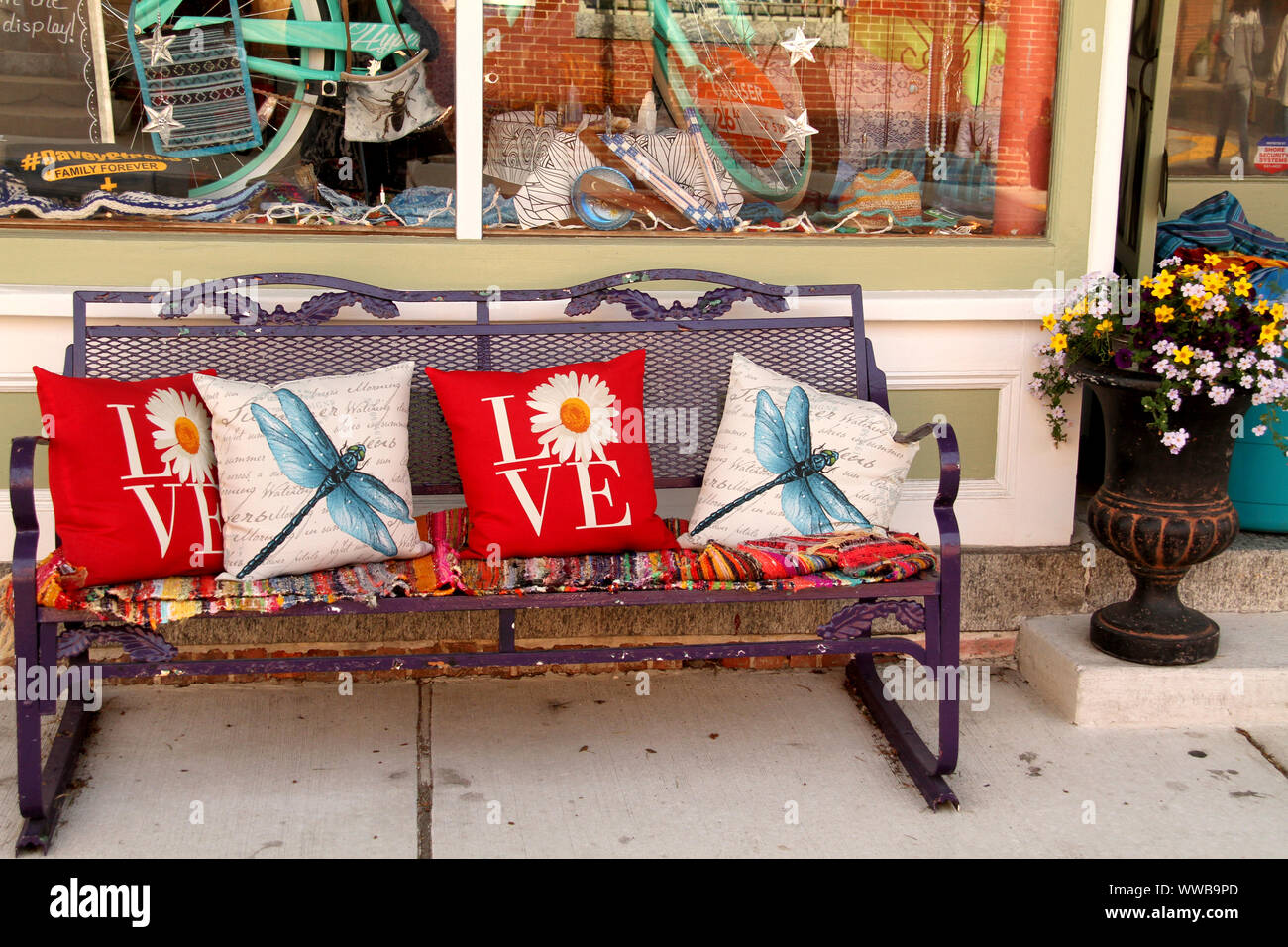 Metal bench on the outside of store, decorated with accent pillows ...
