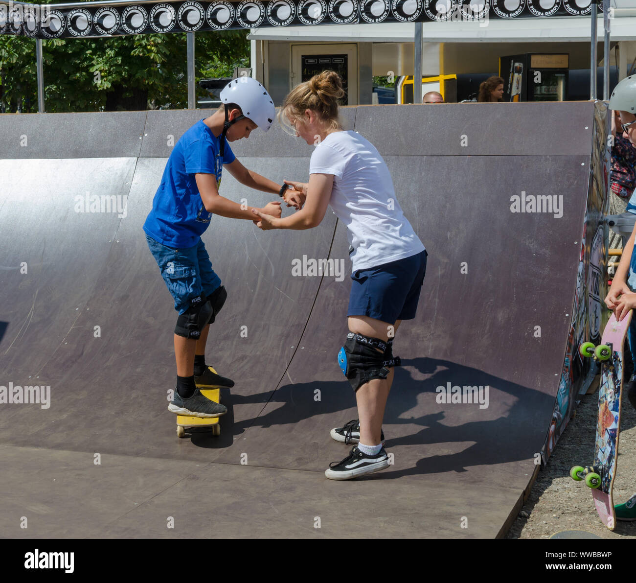 Older girl teach younger boy how to ride a skateboard. Skateboard ...
