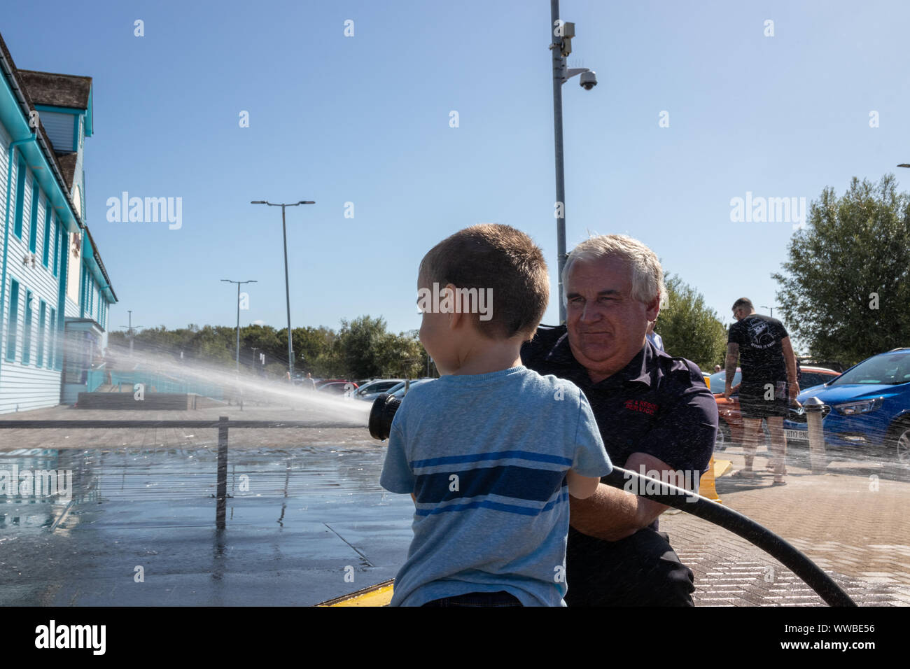 A small boy being shown how to use a fire hose by a fireman Stock Photo ...