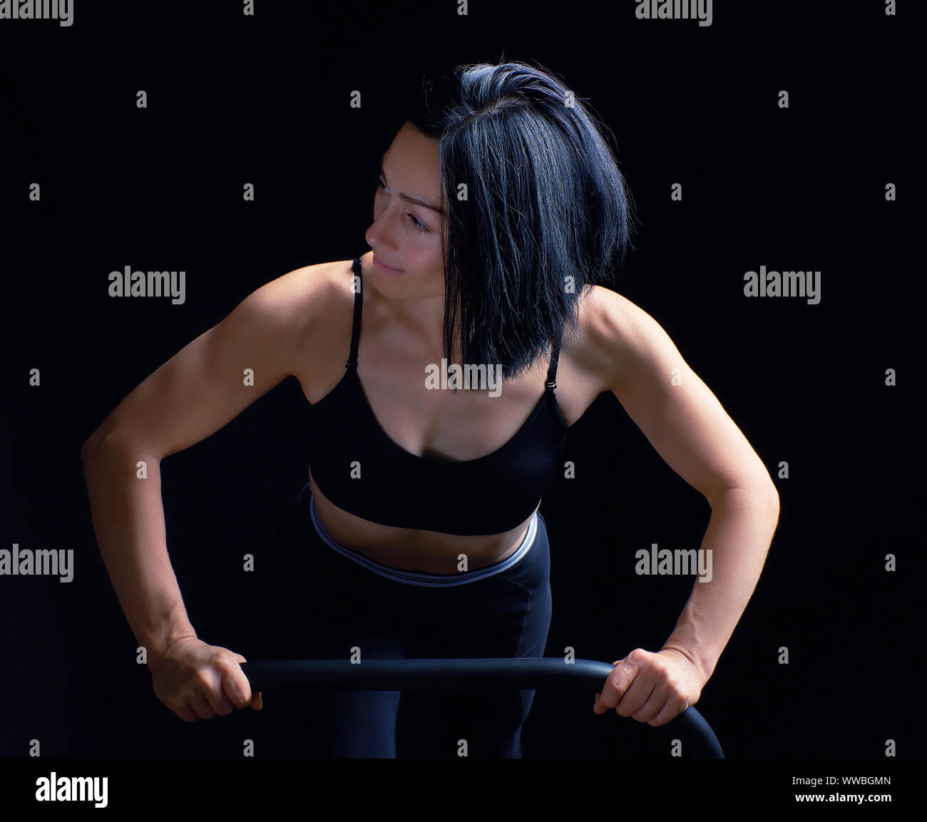 young beautiful athletic girl with muscles in a black bra is wrung out ...