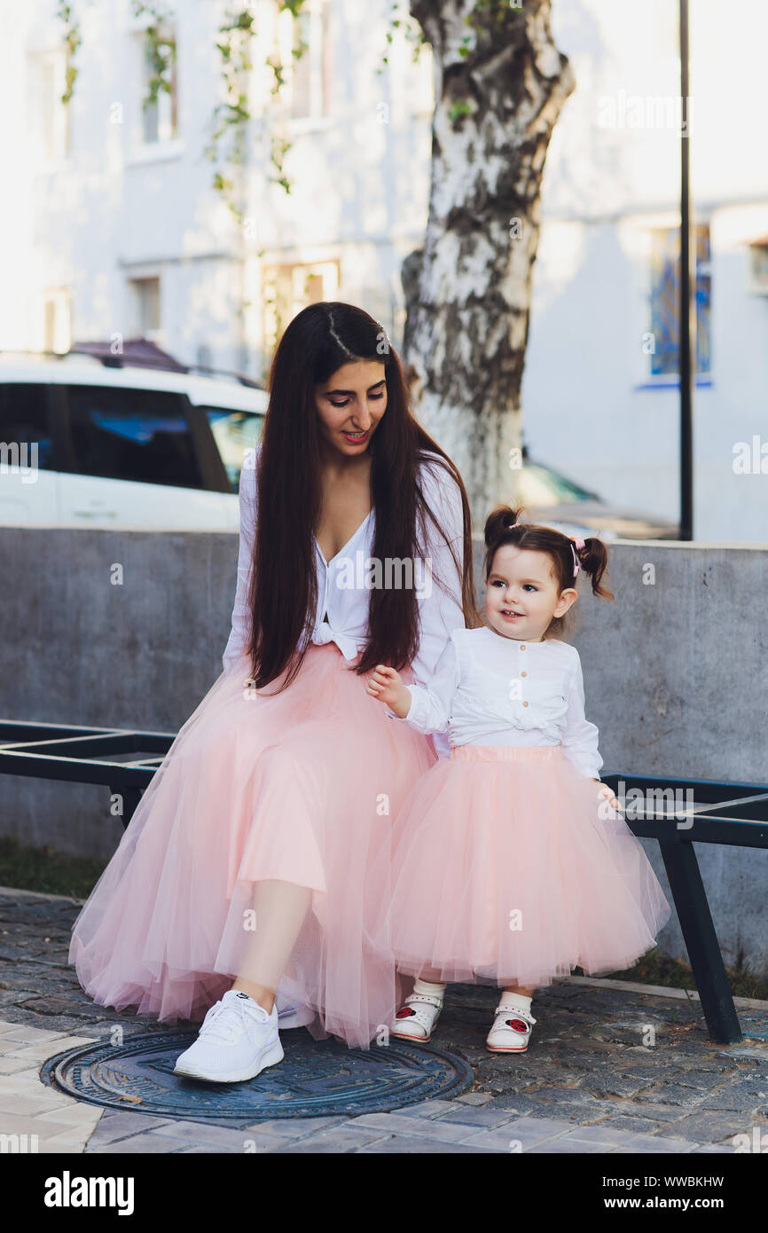 happy mothers and daughters sitting on a bench in a city Park Stock ...