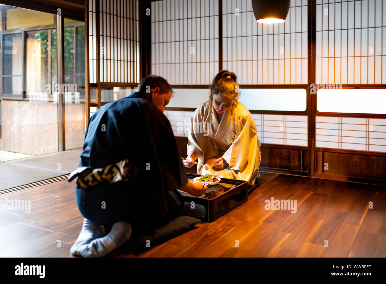 Couple in kimono seiza sitting, holding chopsticks and eating food at ...