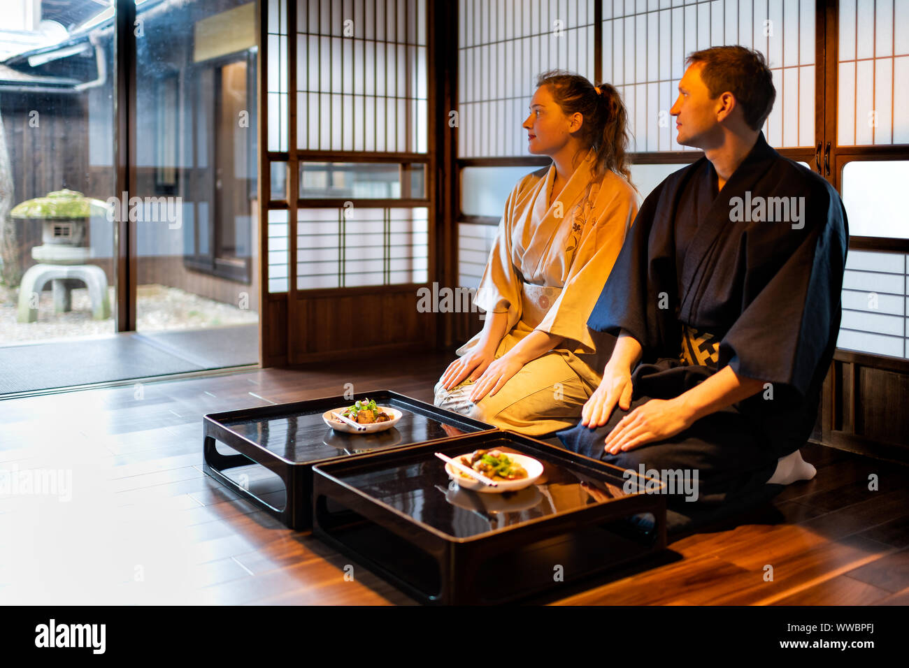 Couple in kimono seiza sitting at traditional Japanese home ryokan room ...