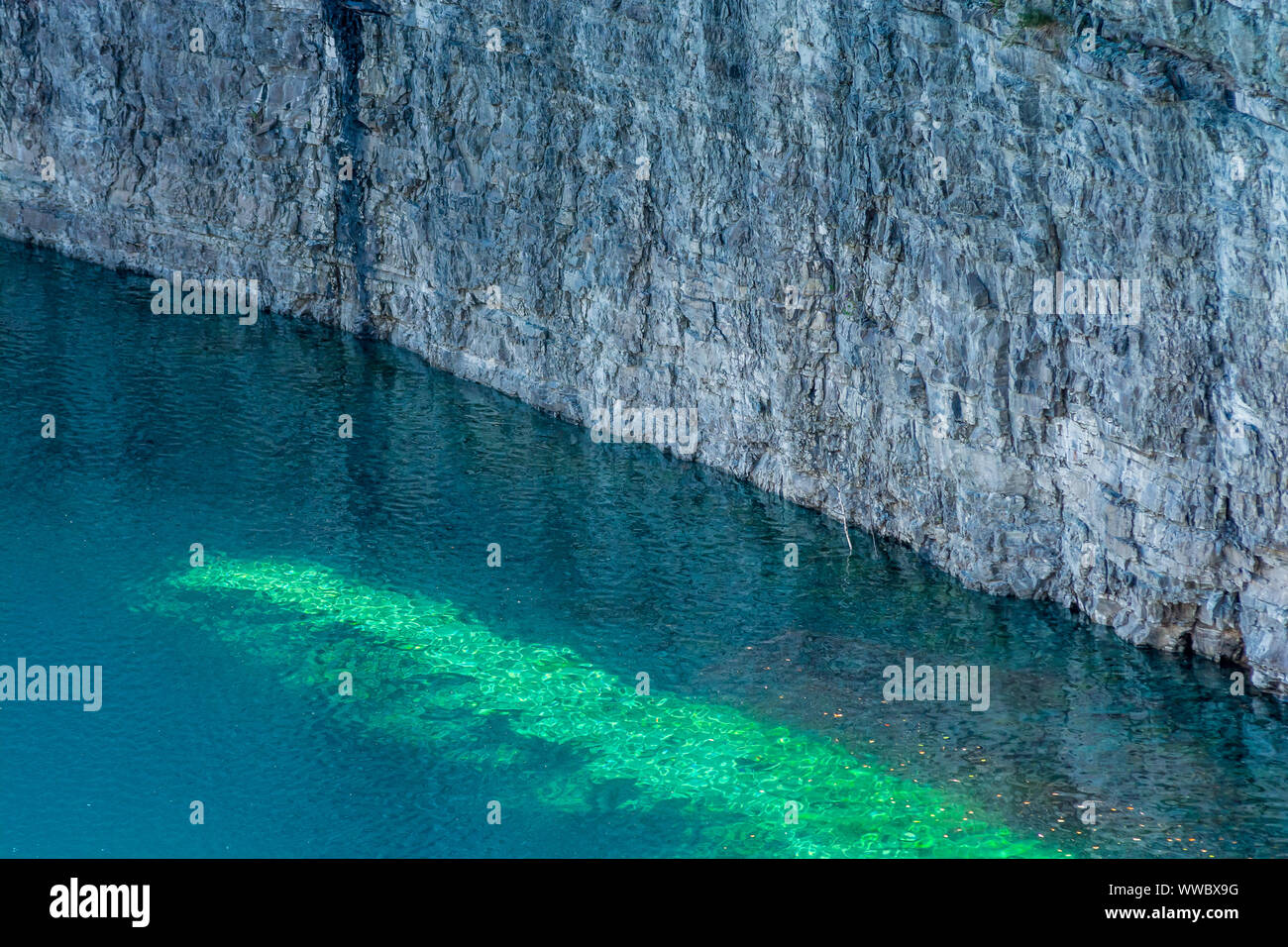 Close up of rocky wall strata showing different layers of green and ...
