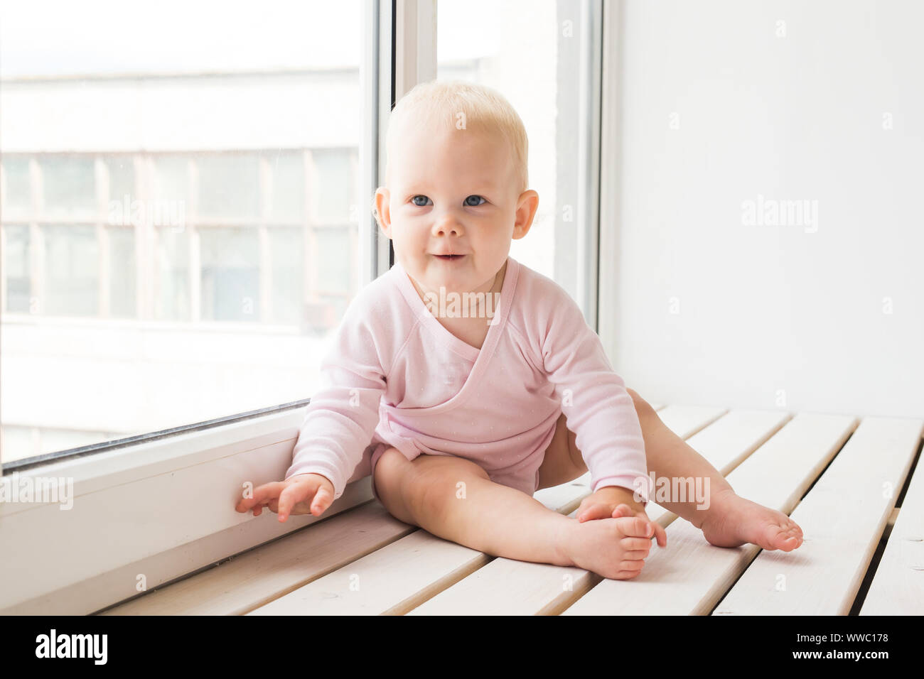 Childhood, family and infant concept - Little baby girl on windowsill ...