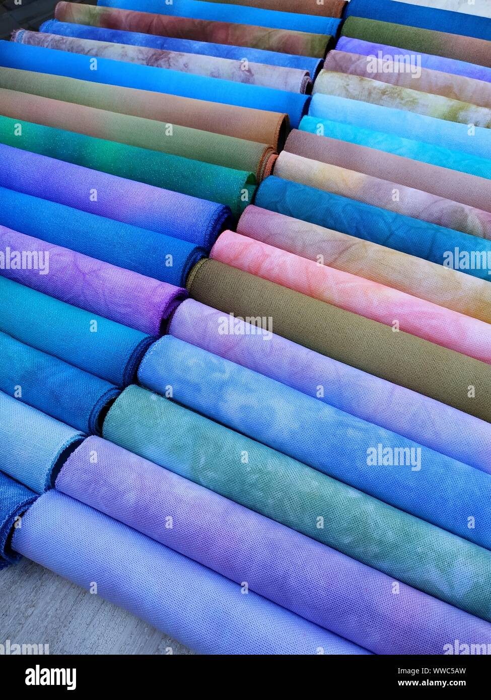 Rolls of colorful fabrics. Dyed fabric for sewing. Cross stitch fabric ...