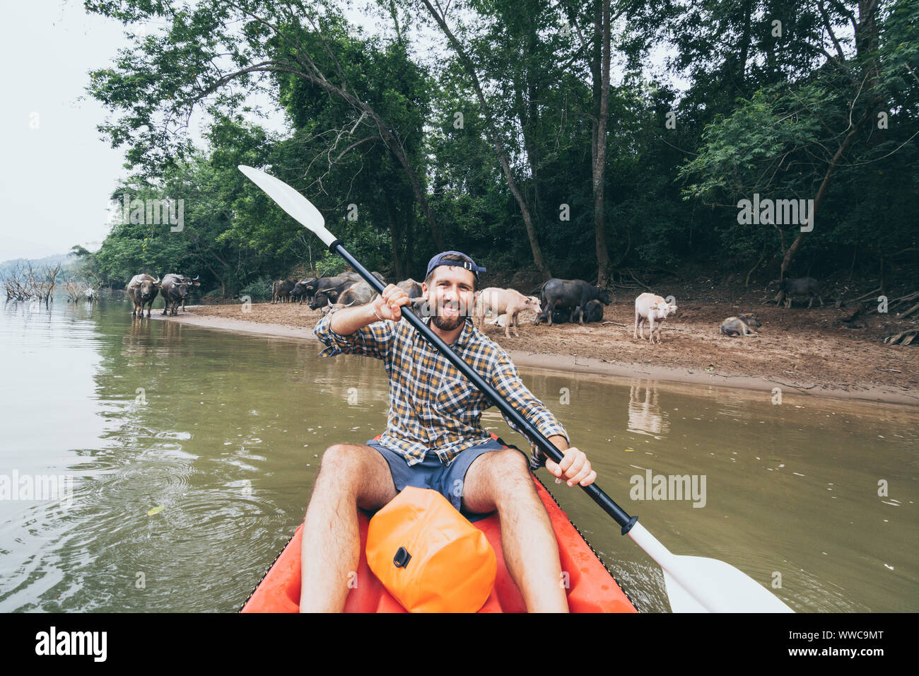 Young bearded Caucasian man paddling in kayak on Mekong river with ...