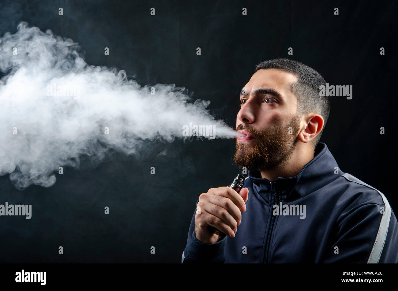 man holding vape e-cigarette or electronic cigarette with white smoke ...