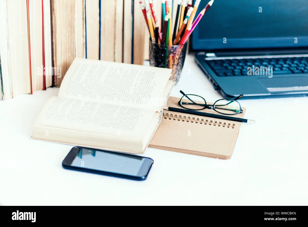 Open textbook, notebook, smartphone, laptop computer, stack of books ...