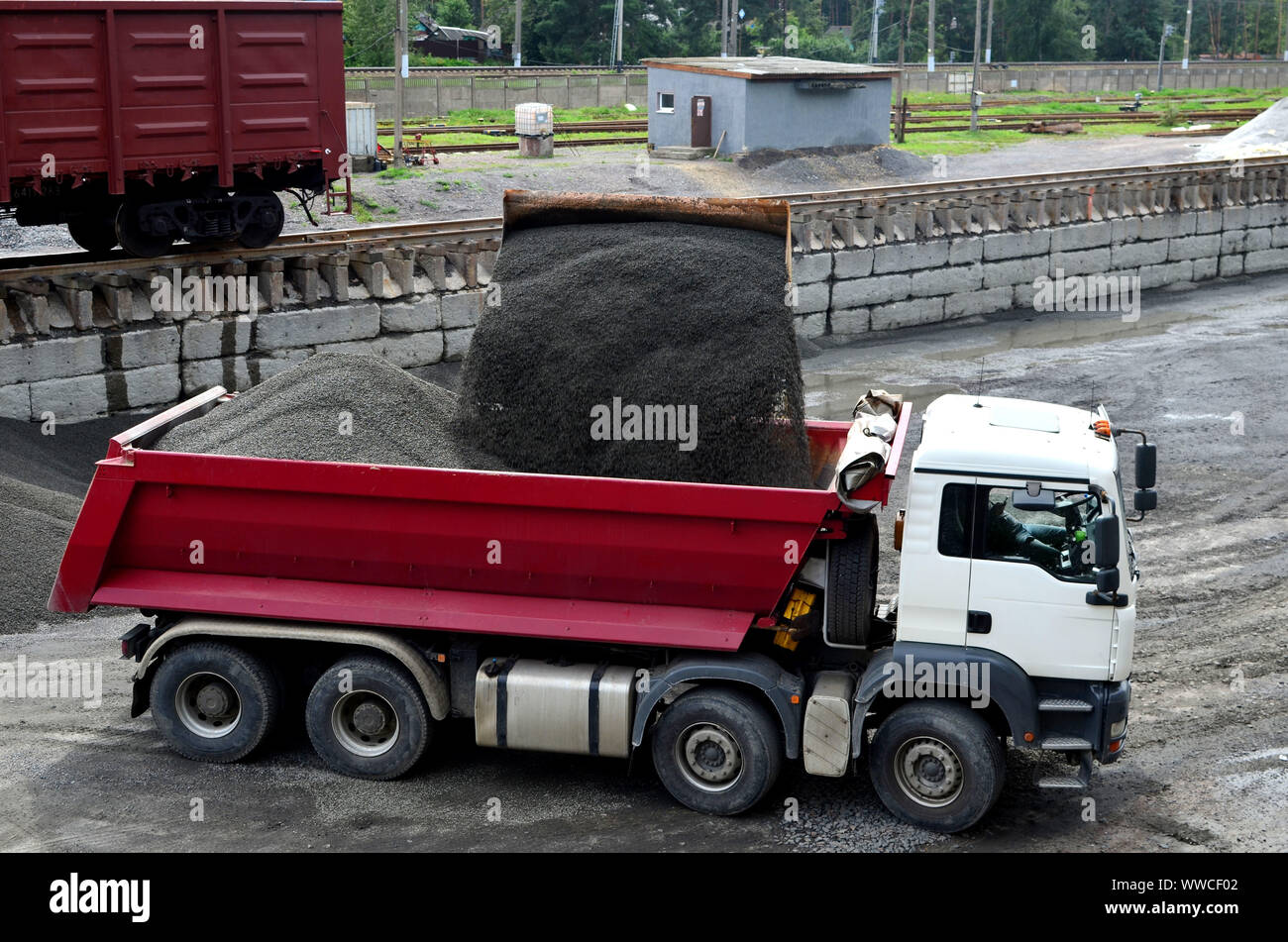 Wheel loader loads gravel into a dump truck at a cargo railway station ...