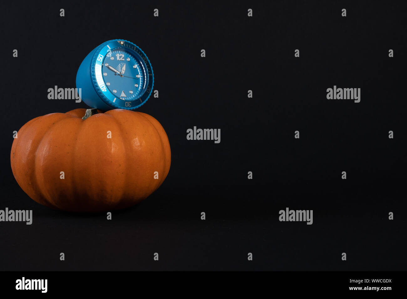 Mini pumpkin with small blue clock on its top, showing its time for ...