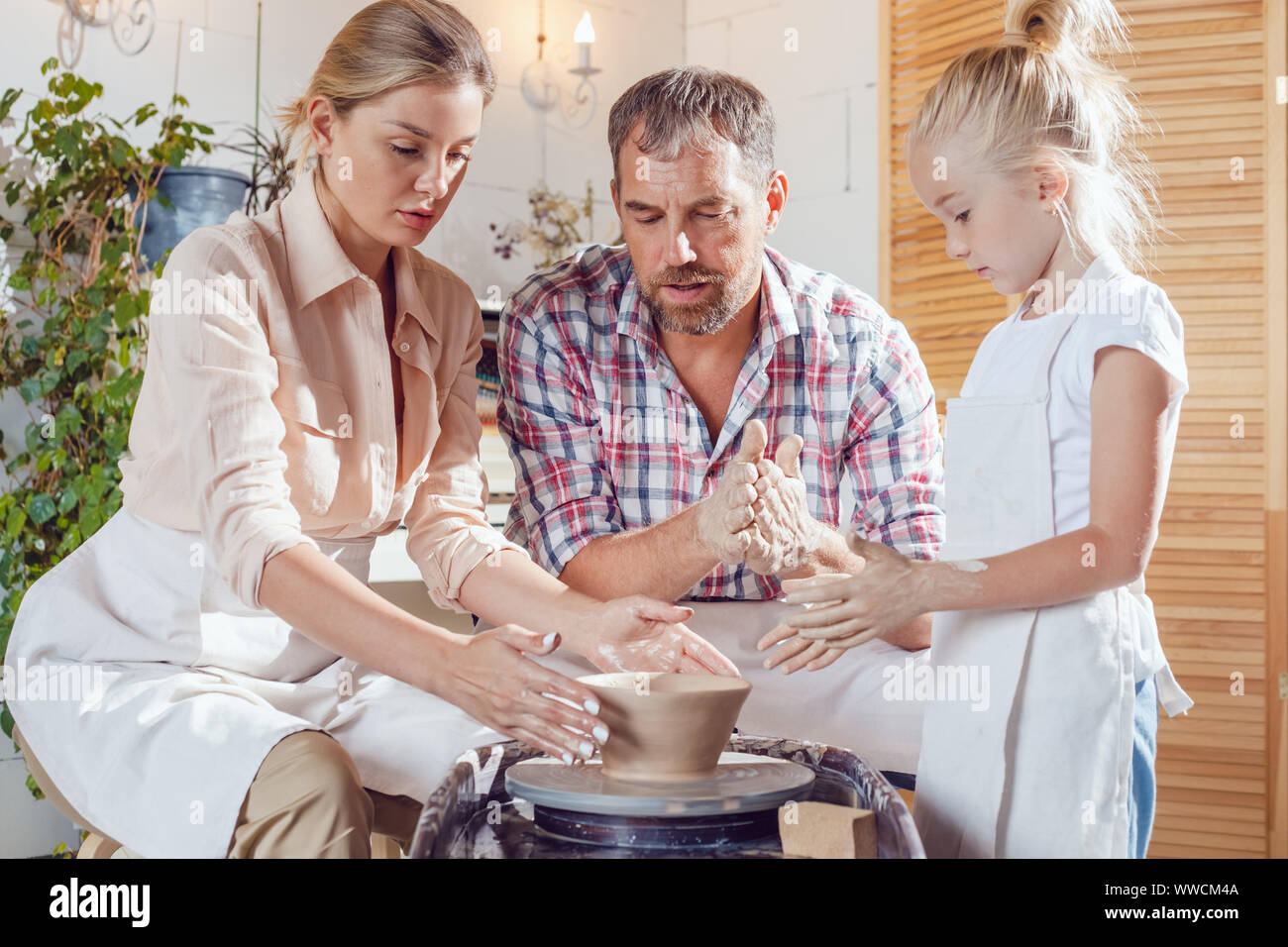 Happy family are sculpting from clay on a pottery wheel. Family of ...