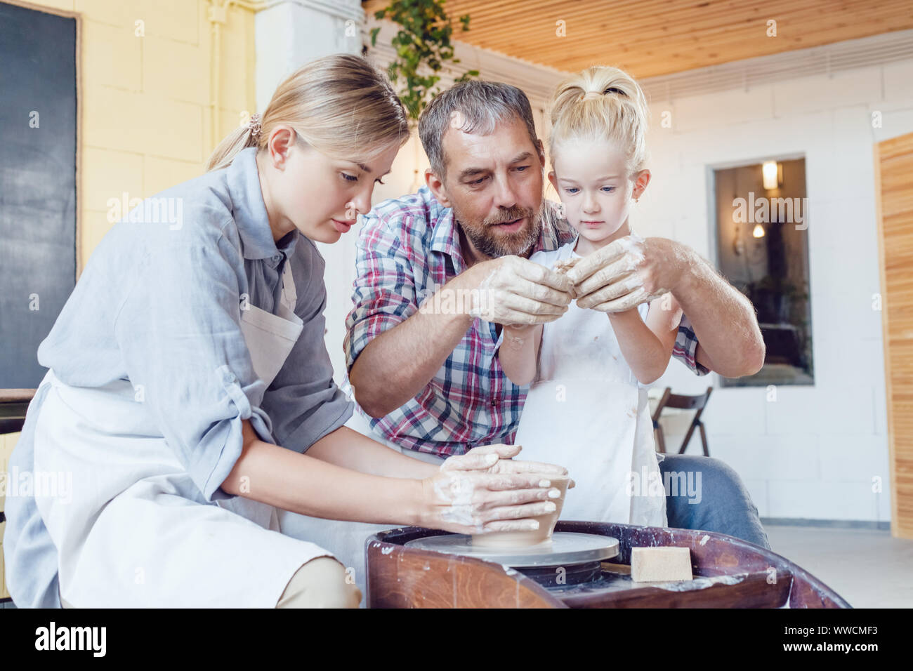 Happy family are sculpting from clay on a pottery wheel. Family of ...