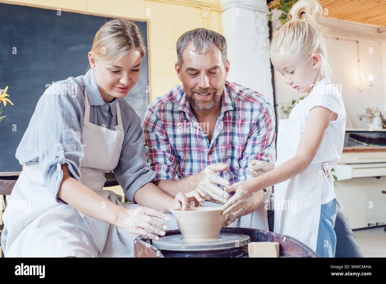 Happy family are sculpting from clay on a pottery wheel. Family of ...