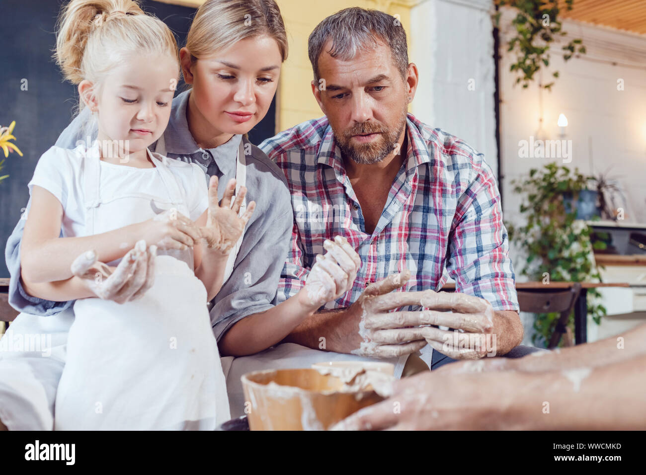 Happy family are sculpting from clay on a pottery wheel. Family of ...