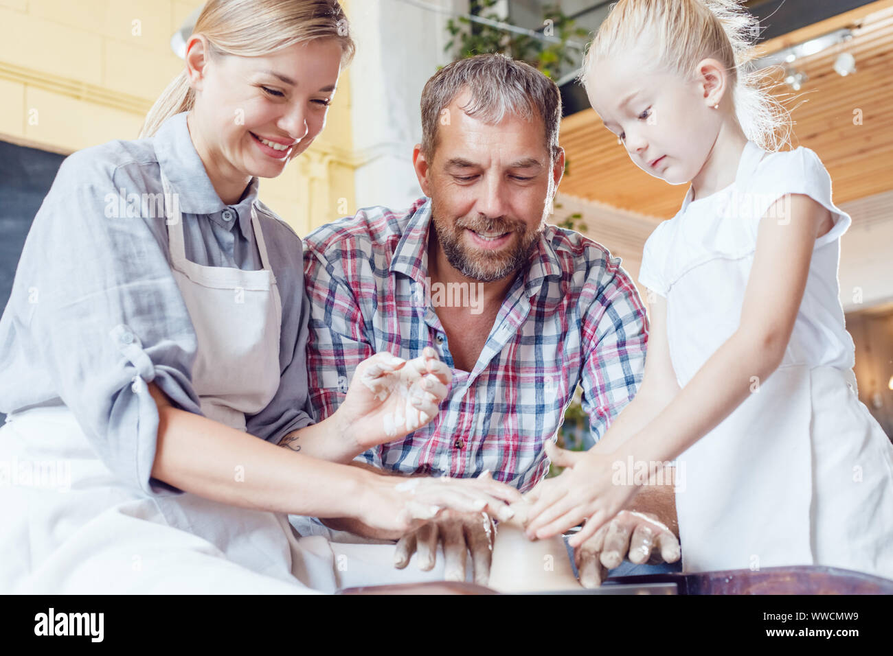 Happy family are sculpting from clay on a pottery wheel. Family of ...