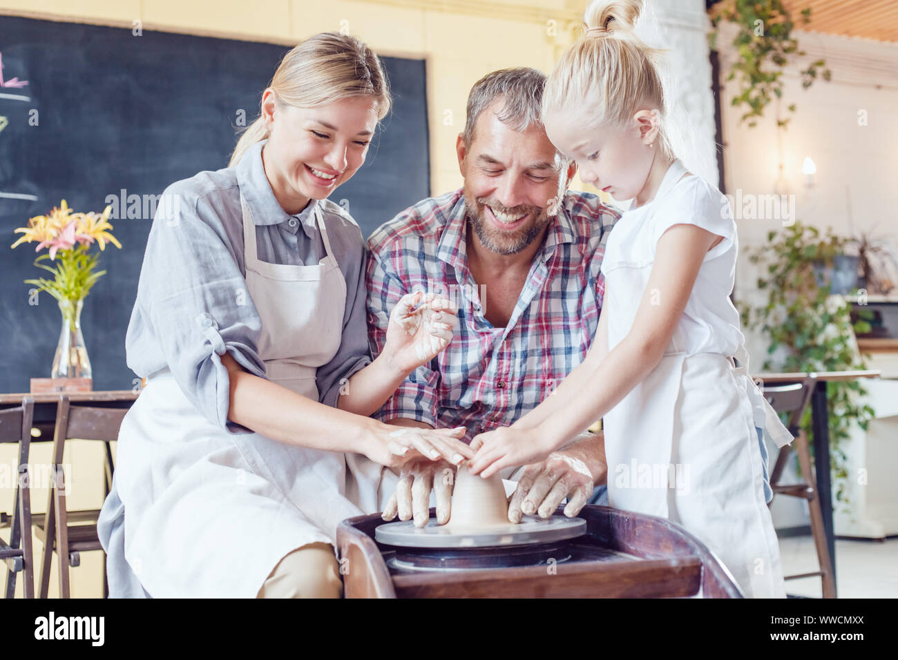 Happy family are sculpting from clay on a pottery wheel. Family of ...