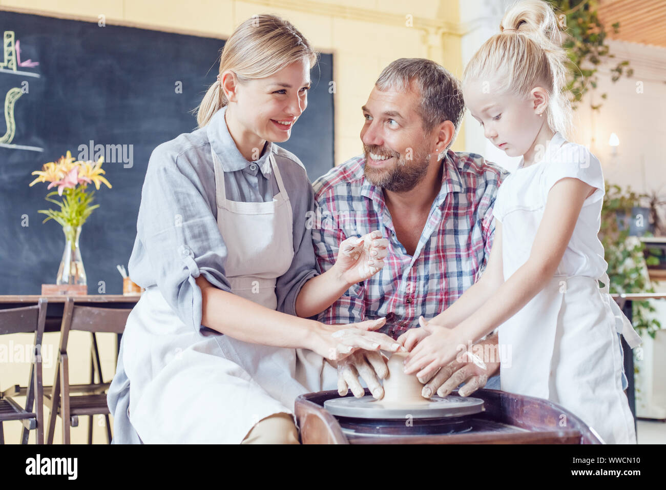 Happy family are sculpting from clay on a pottery wheel. Family of ...
