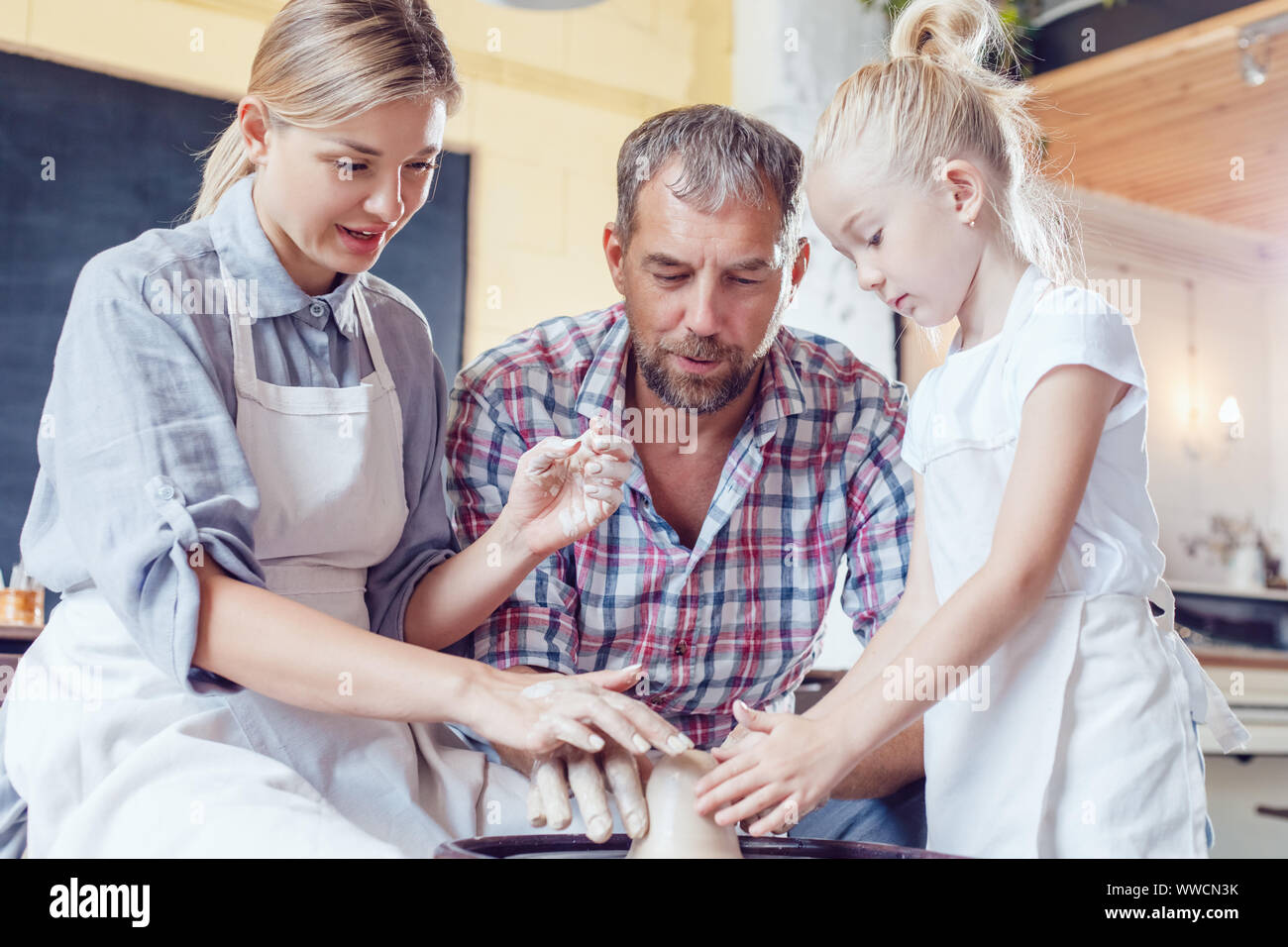 Happy family are sculpting from clay on a pottery wheel. Family of ...