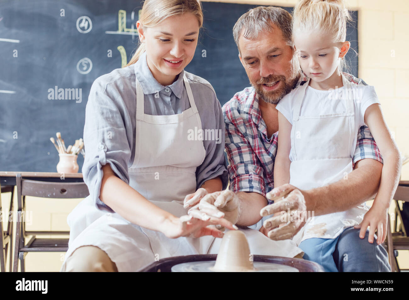 Happy family are sculpting from clay on a pottery wheel. Family of ...