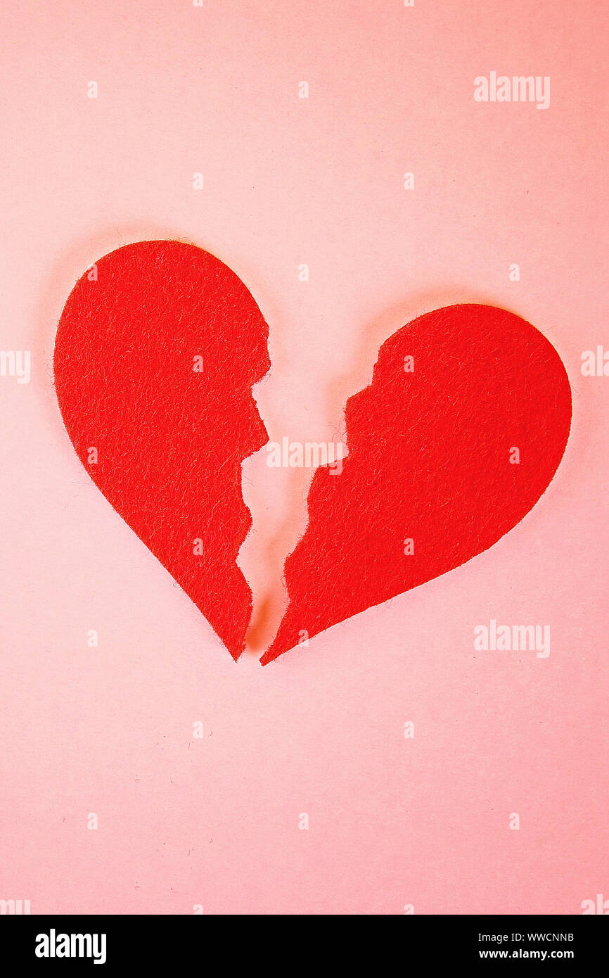 Red felt heart broken into two halves on a pink background Stock Photo ...