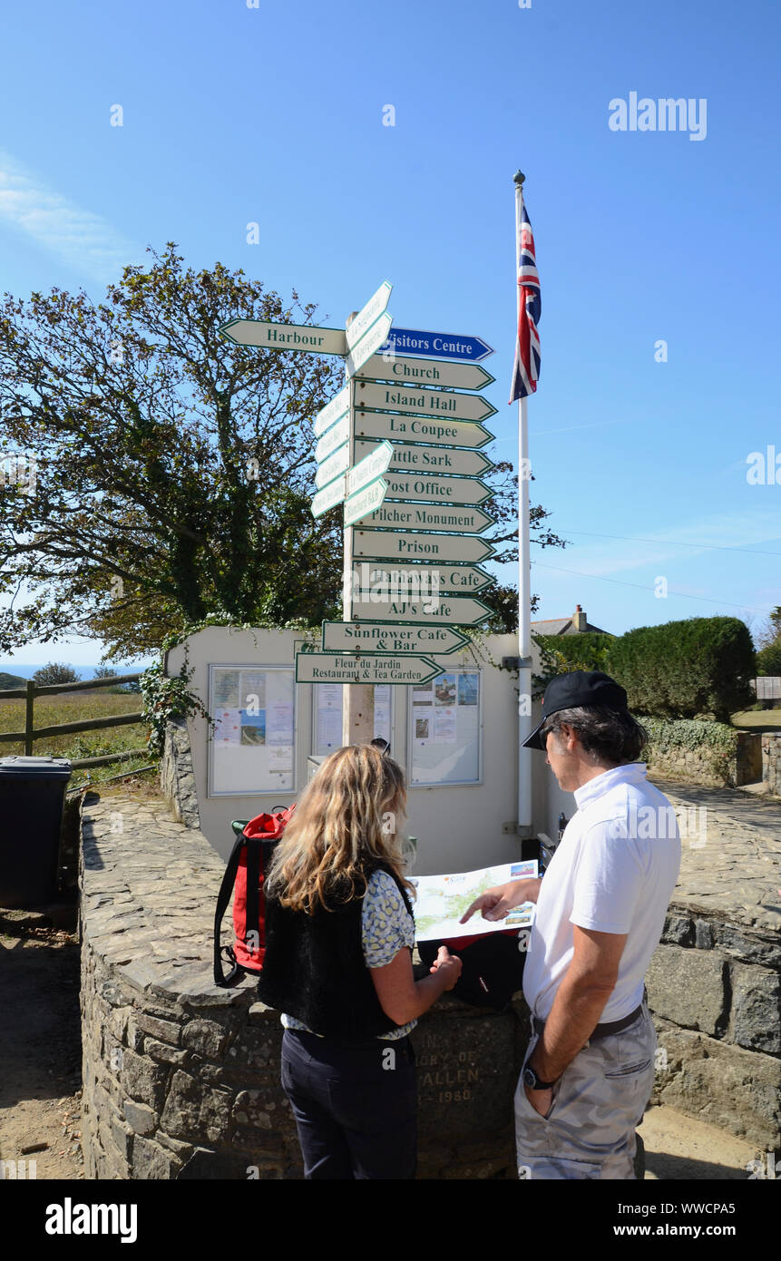 Male and female Tourists looking at maps and information signs on the ...