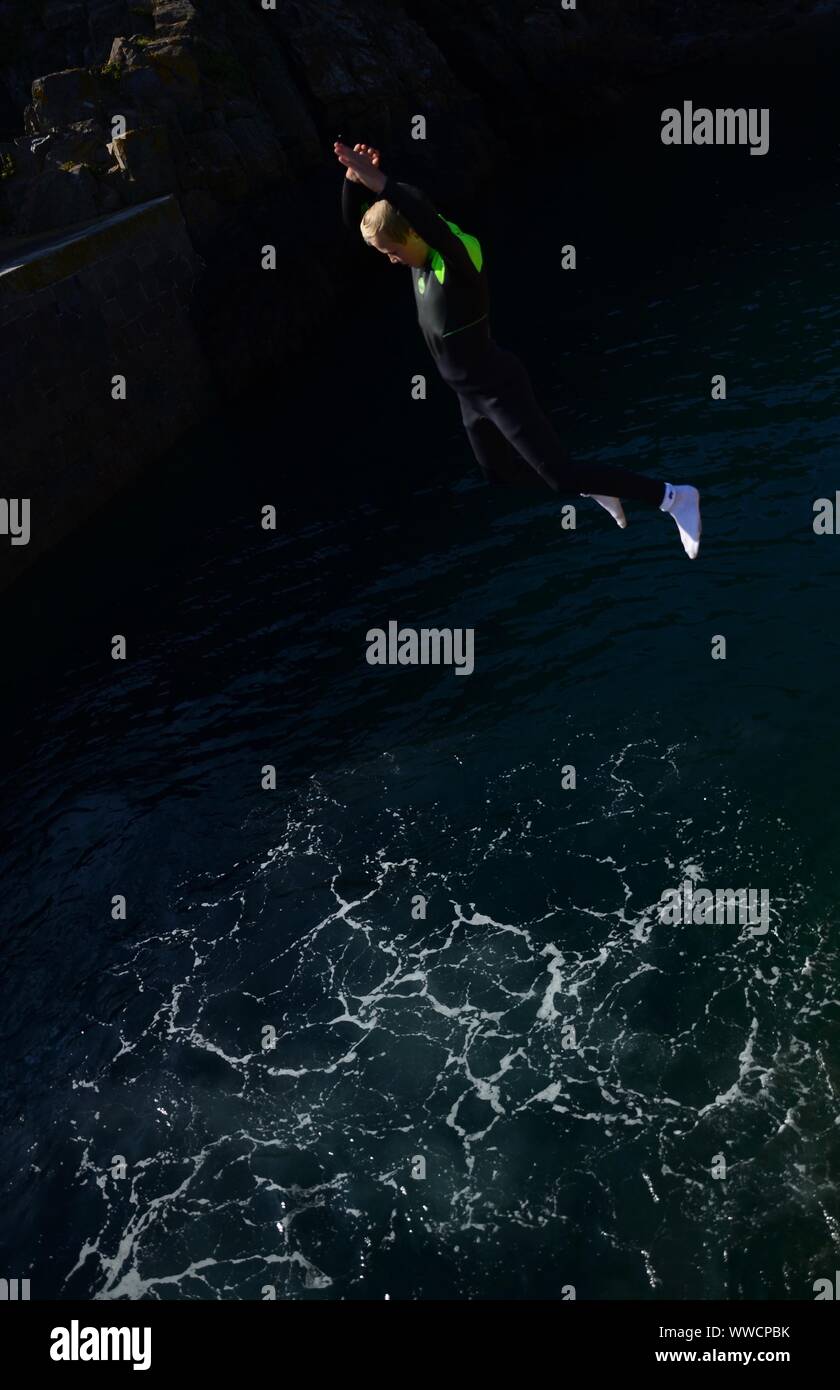 Child in wetsuit jumping off quayside into harbour on Build-A-Boat fun ...