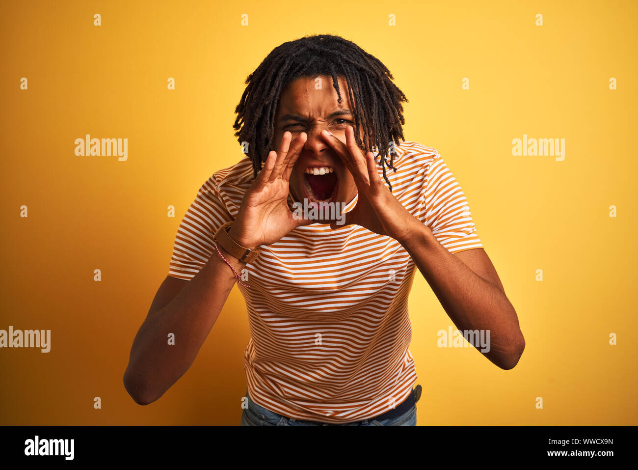 Afro man with dreadlocks wearing striped t-shirt standing over isolated ...