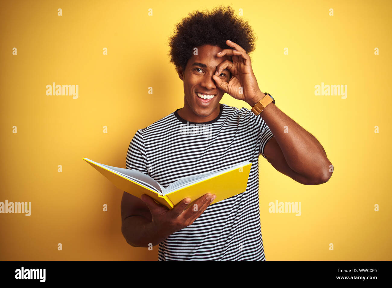 Afro american student man reading book standing over isolated yellow ...