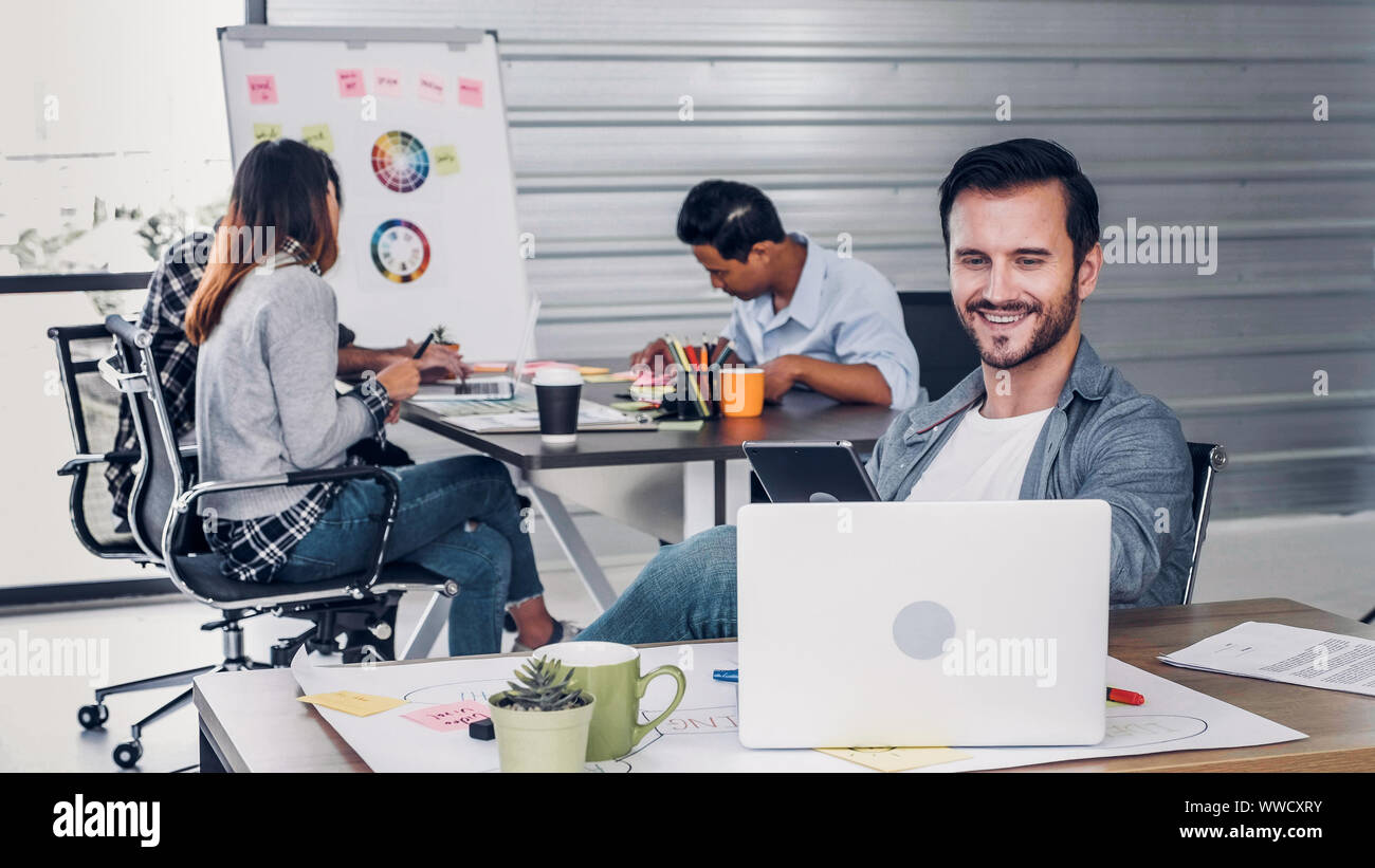 Creative designer director checking work on laptop while team is in ...