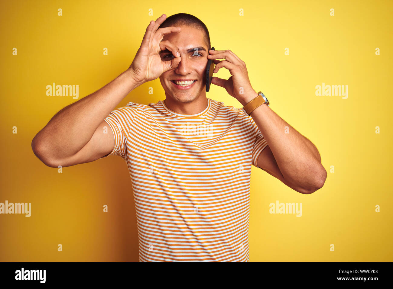 Young handsome man talking using smartphone over yellow isolated ...