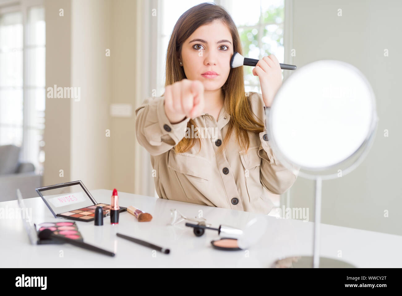 Beautiful young woman using make up cosmetics applying color using ...