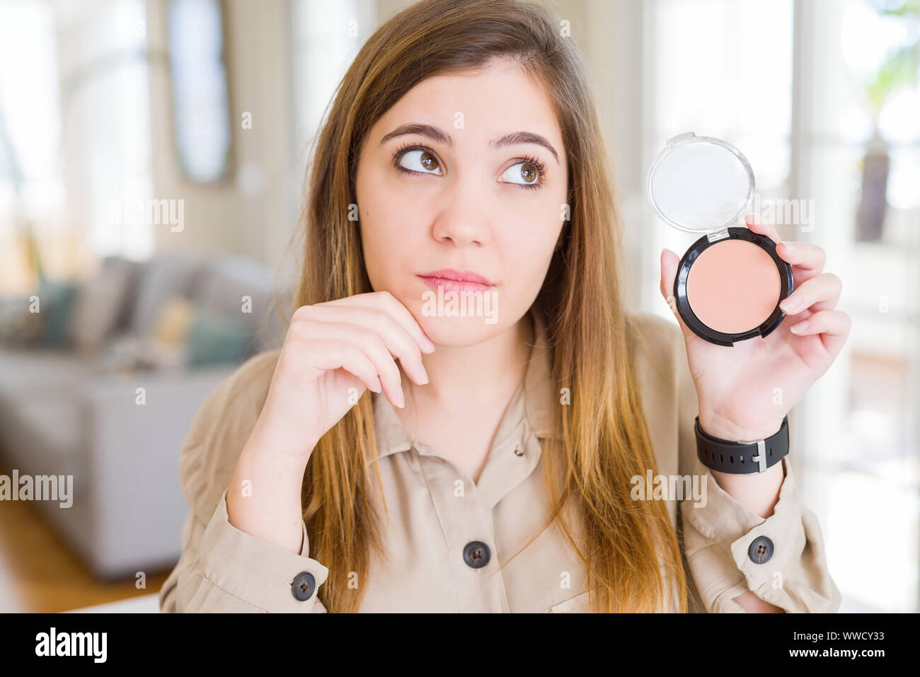 Beautiful young woman using make up cosmetics applying powder serious ... Beautiful young woman using make up cosmetics applying powder serious ...