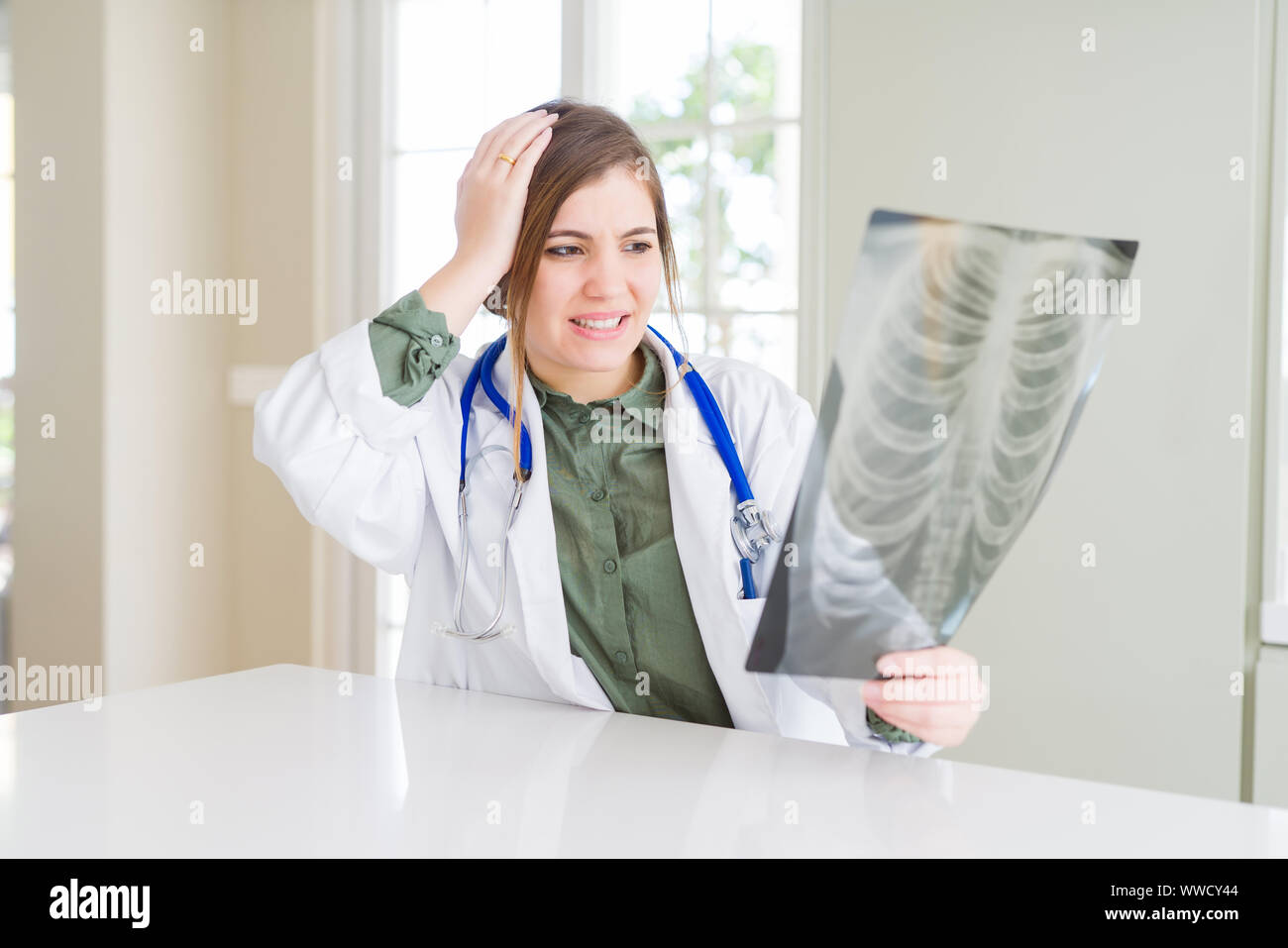 Beautiful young doctor woman looking at chest radiography stressed with ...