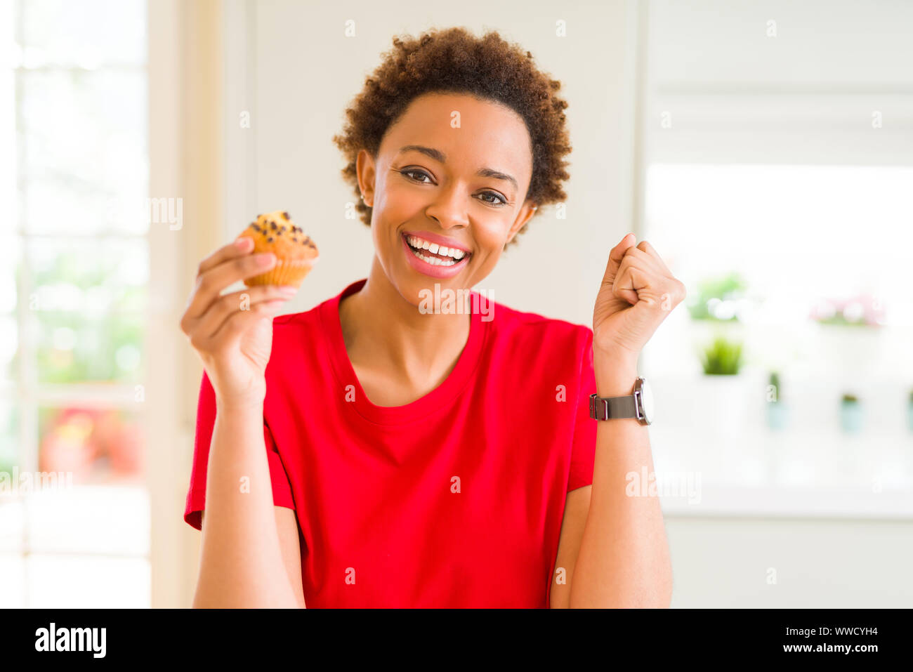 Young african american woman eating chocolate chips muffins screaming ...