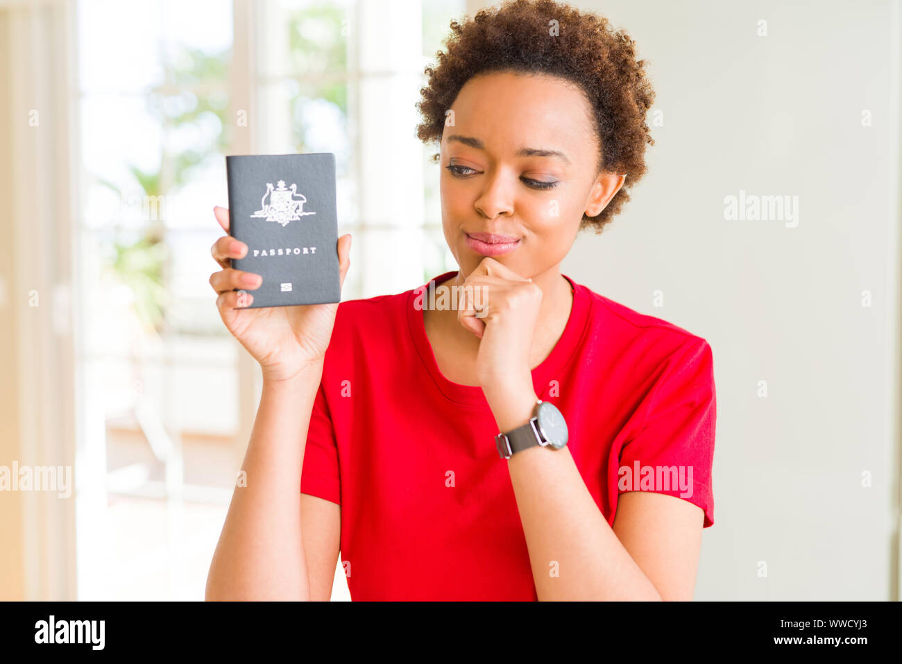 Young african american woman holding Australian passport serious face ...