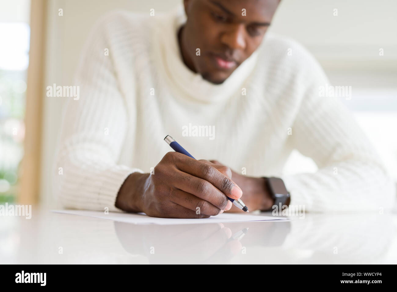 Close up of african man writing a note on a paper Stock Photo - Alamy