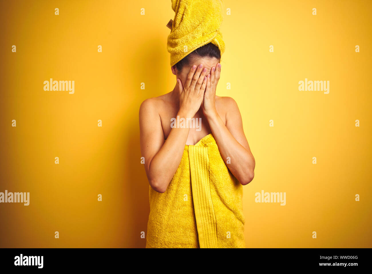 Beautiful woman wearing shower towel on body and head over yellow ...