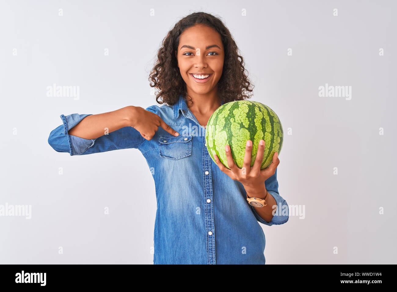 Young brazilian woman holding watermelon standing over isolated white ...