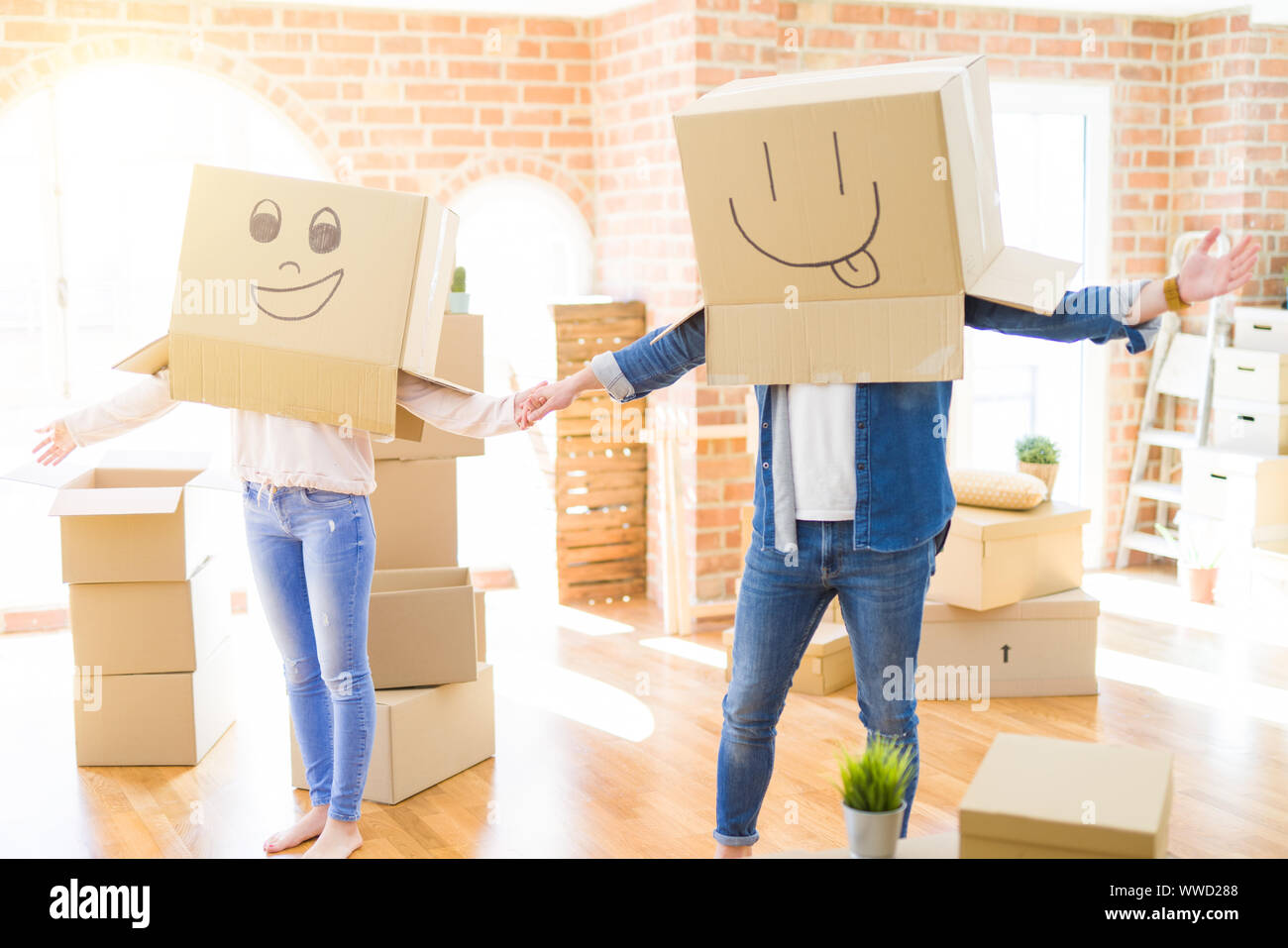 Couple having fun at new apartment wearing boxes with funny faces over ...