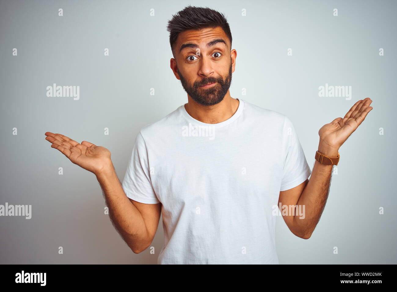 Young indian man wearing t-shirt standing over isolated white ...